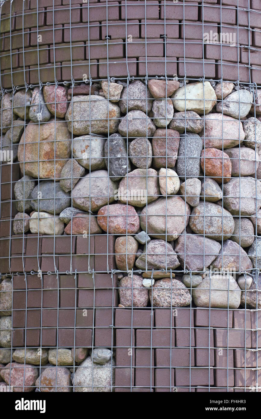 Wall with differently shaped stones in metal mesh Stock Photo - Alamy