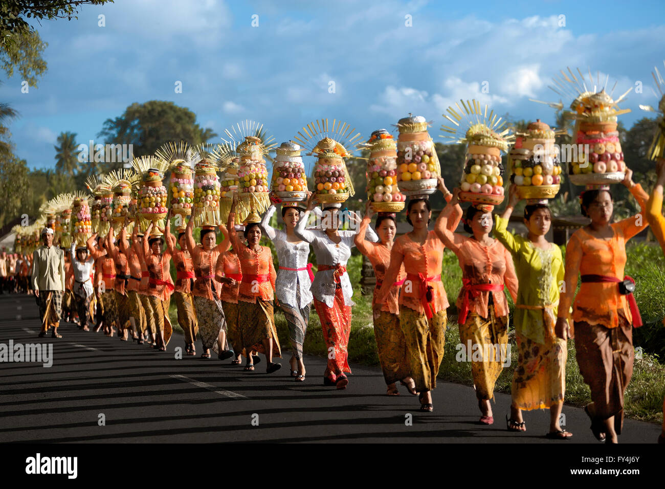 A graceful Balinese woman dressed in traditional attire walks towards a ...