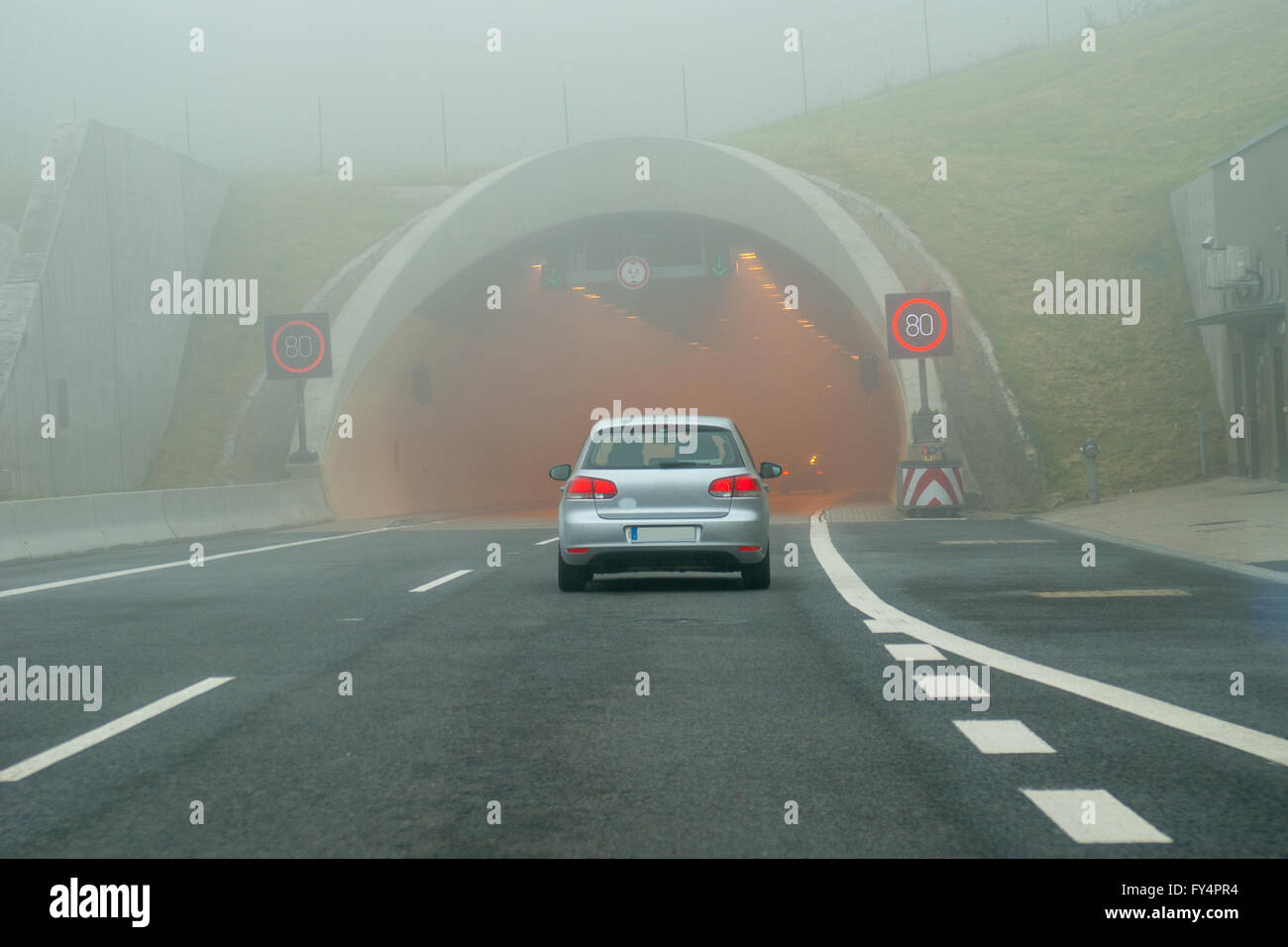 car before tunnel with speed limit signs on foggy road Stock Photo - Alamy