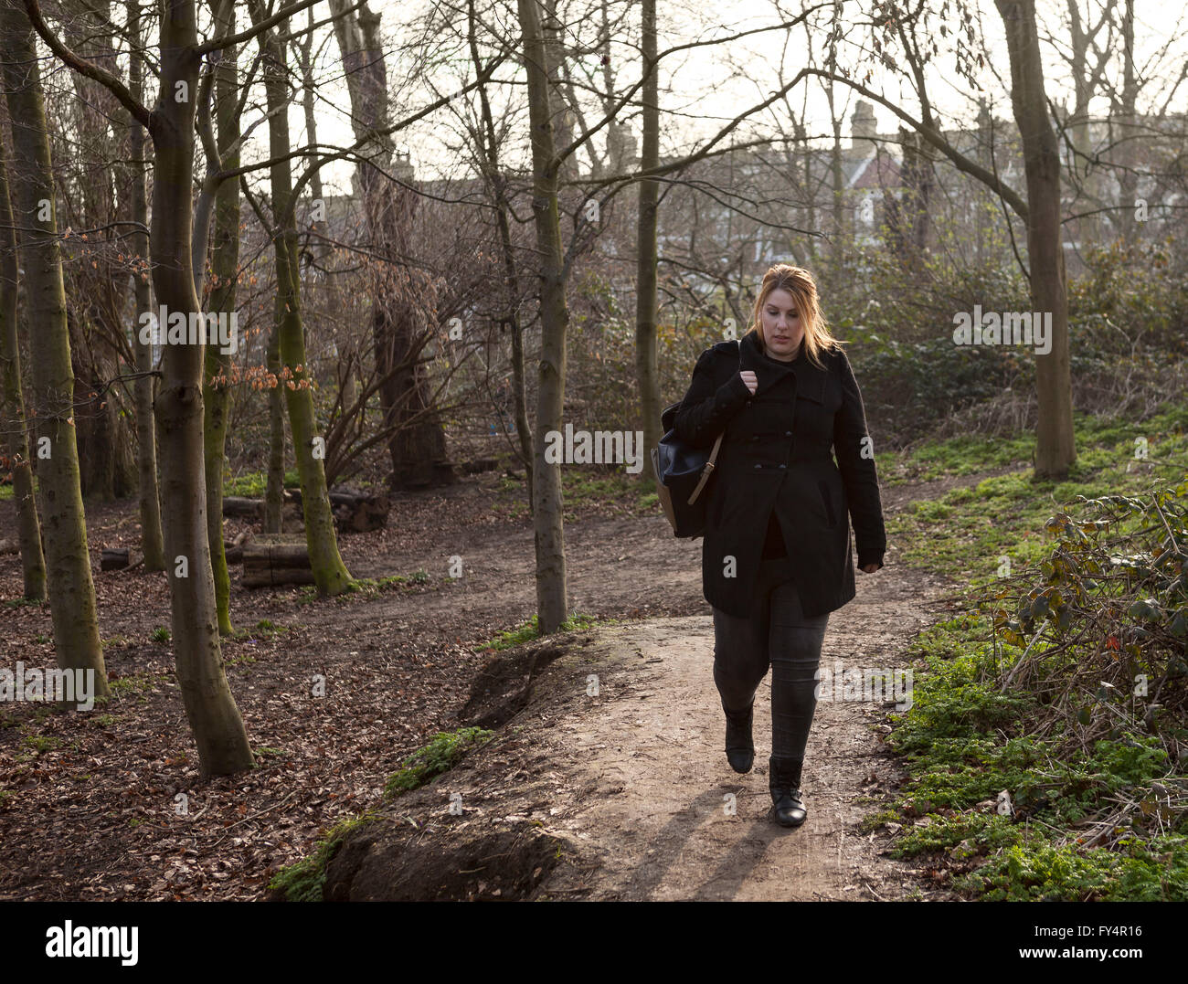Walking Home. A young woman is taking the short cut through the park to ...