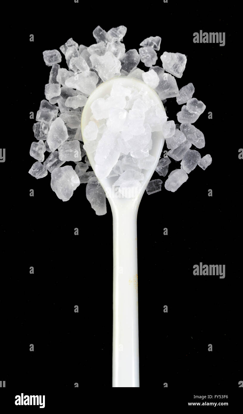Coarse rock salt in a white spoon isolated on a black background Stock ...