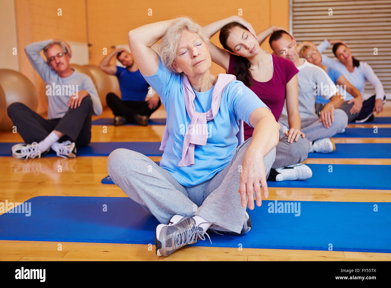 Group doing stretching exercises in back training class in a fitness ...