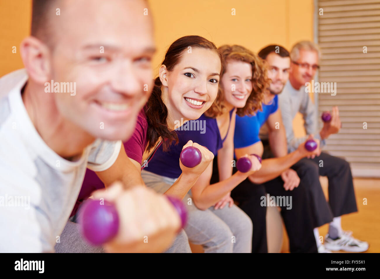 Happy group lifting dumbbells in a fitness center gym Stock Photo - Alamy