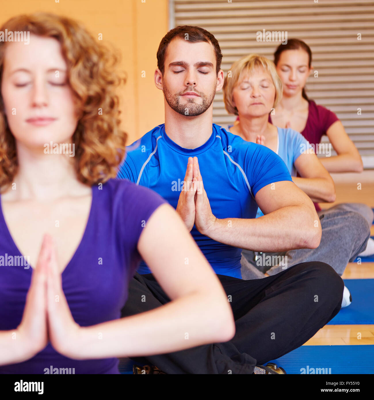 Meditation in a mixed yoga group in a fitness center Stock Photo - Alamy