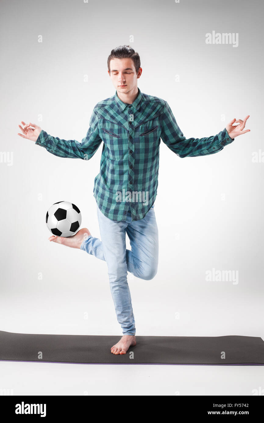 Portrait of young man, practicing yoga with football ball Stock Photo ...
