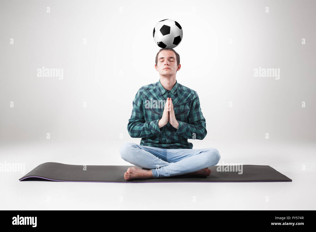 Portrait of young man, practicing yoga with football ball Stock Photo ...
