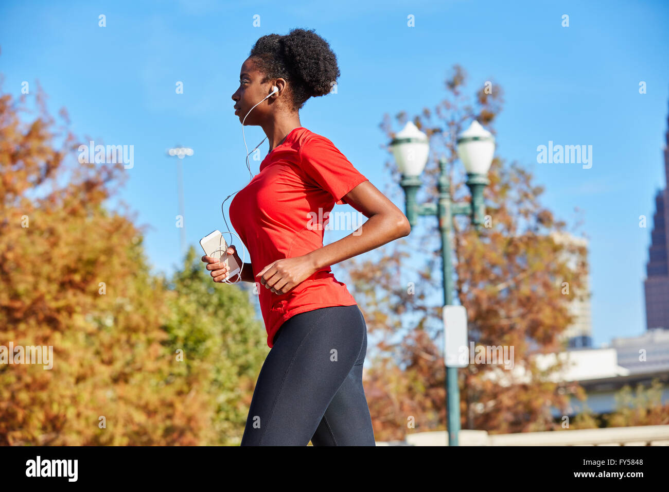 Runner girl running and listening music earphones in the city park ...