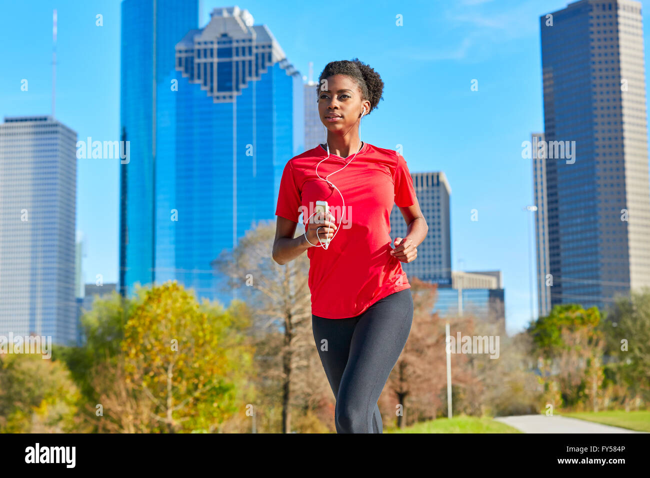 Runner girl running and listening music earphones in the city park ...