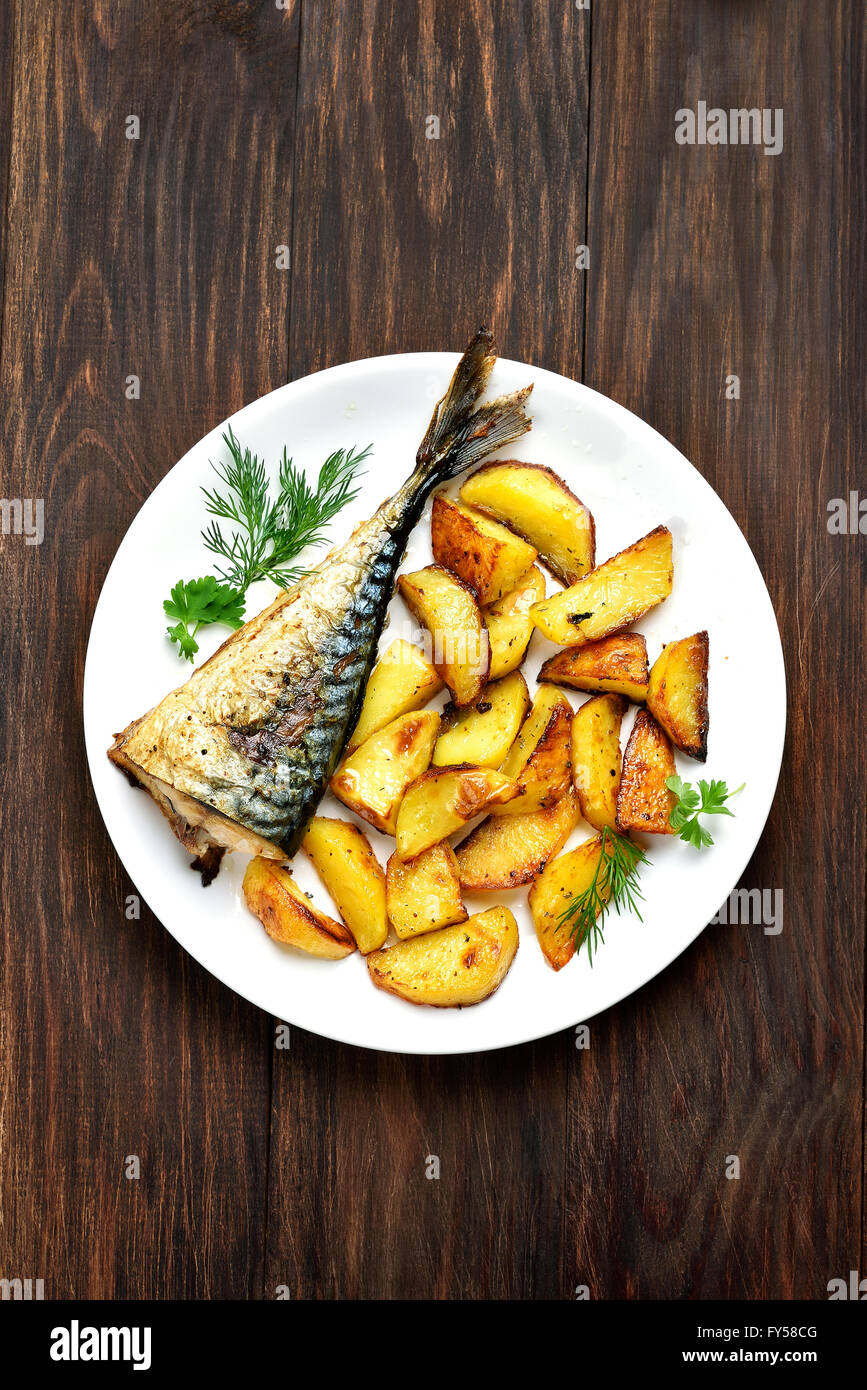 Baked potato wedges and mackerel fish on wooden background, top view ...