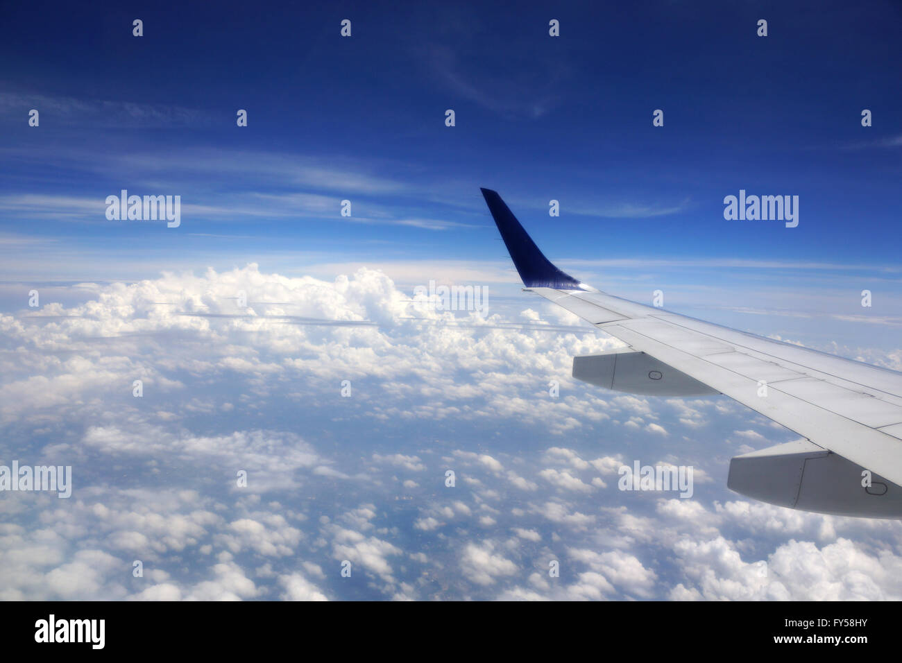 Aerial high in the sky shot from above the clouds with the wing of a ...