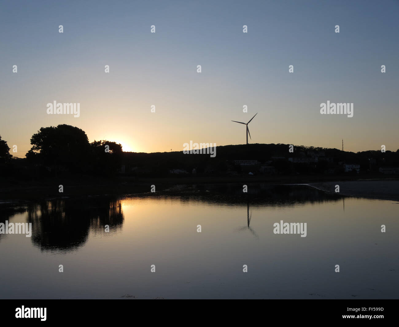 Sunsets over Stream leading to beach with windmill visible above the ...