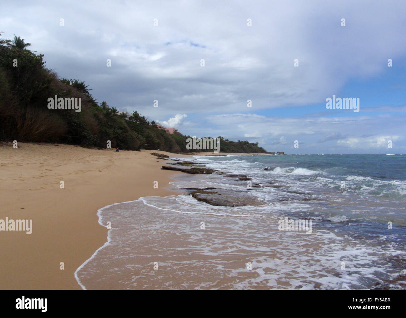 Beach rocks in the water and foot prints in the sand, San Juan, Puerto ...