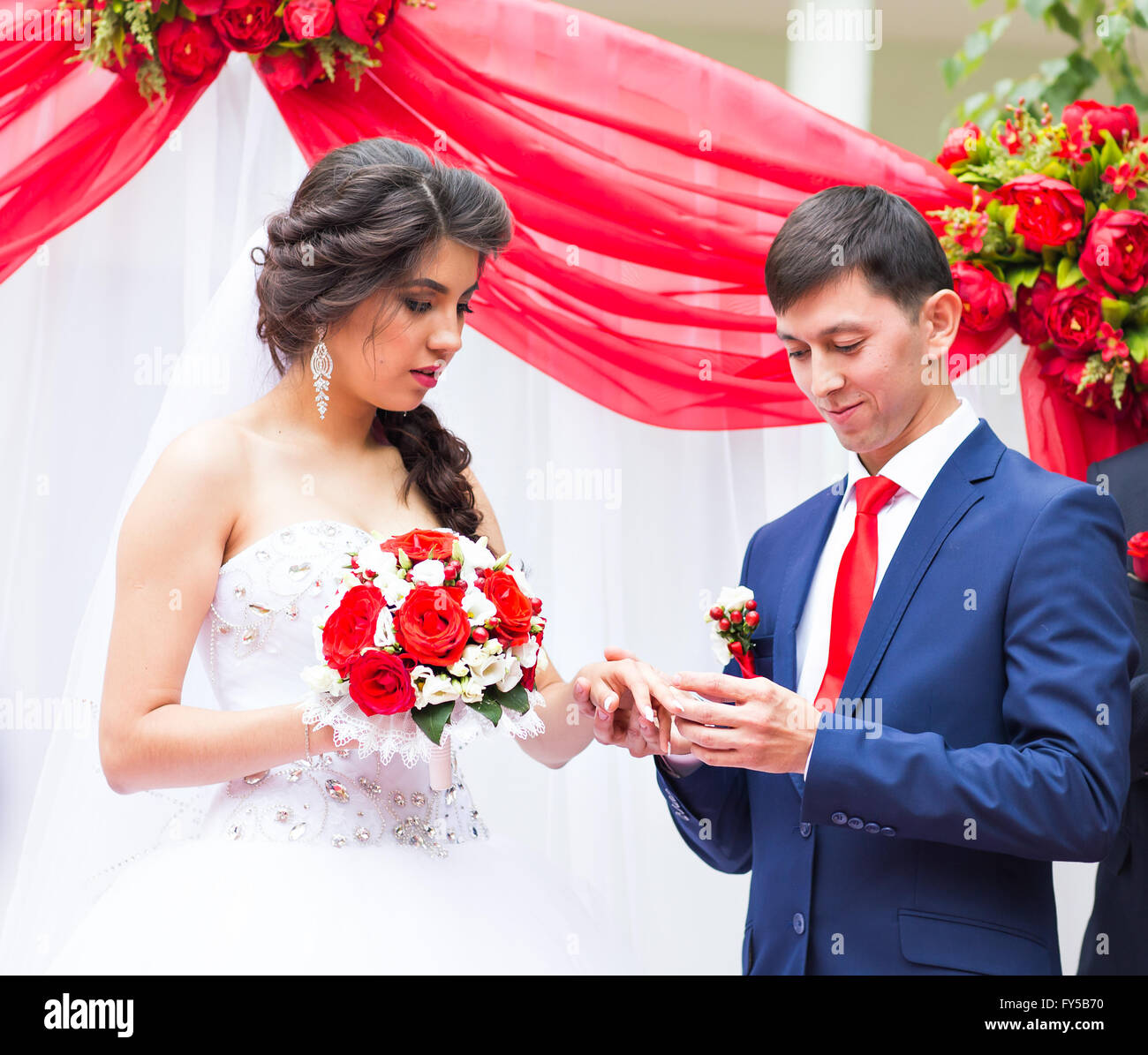 groom putting wedding ring on bride hand Stock Photo - Alamy