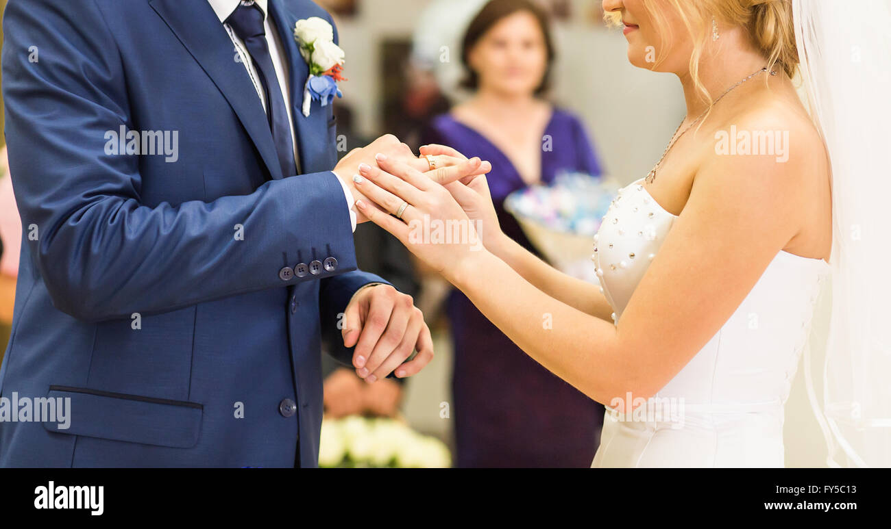Bride slipping ring on finger of groom at wedding Stock Photo - Alamy
