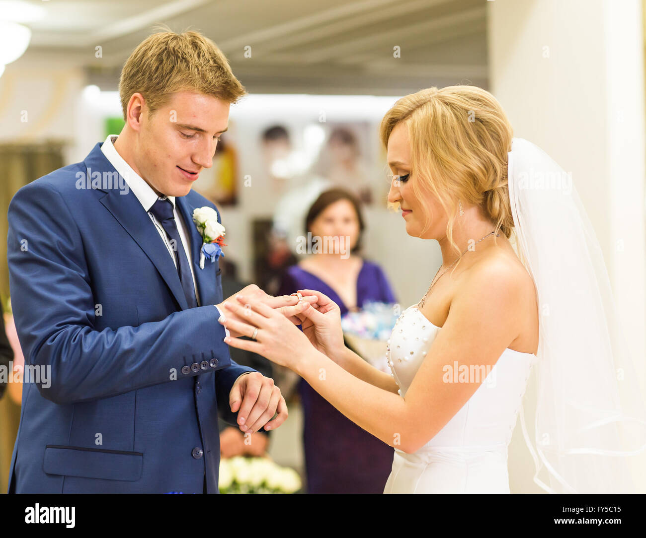 Bride slipping ring on finger of groom at wedding Stock Photo - Alamy