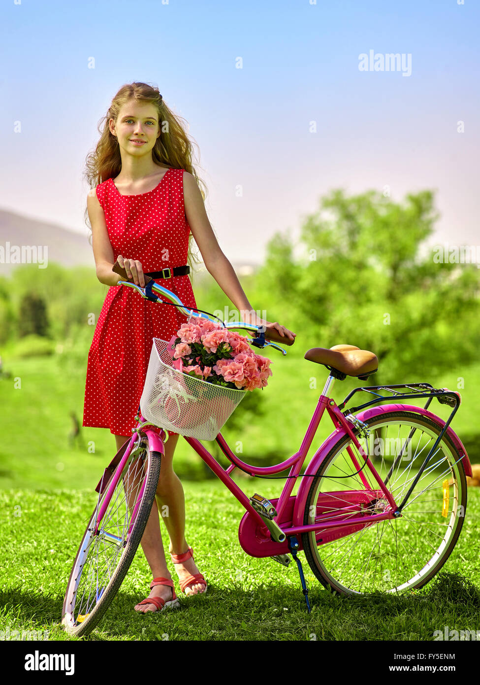 Girl wearing red polka dots dress rides bicycle into park Stock Photo ...