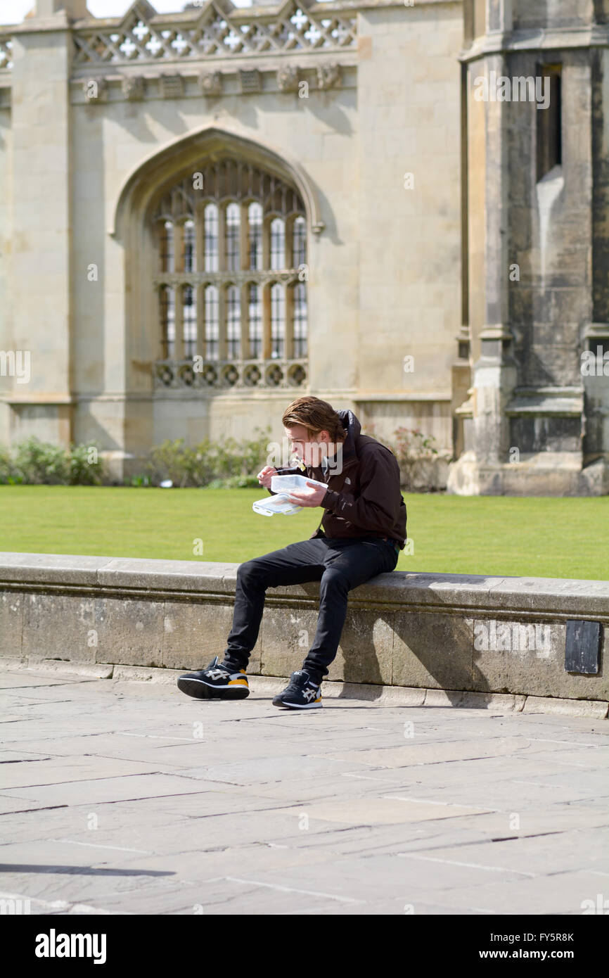 Young man sat on wall eating takeaway meal outside Corpus Christi ...