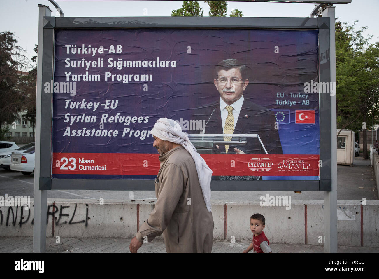 A syrian refugee man and his kid is walking by a bilboard promoting ...