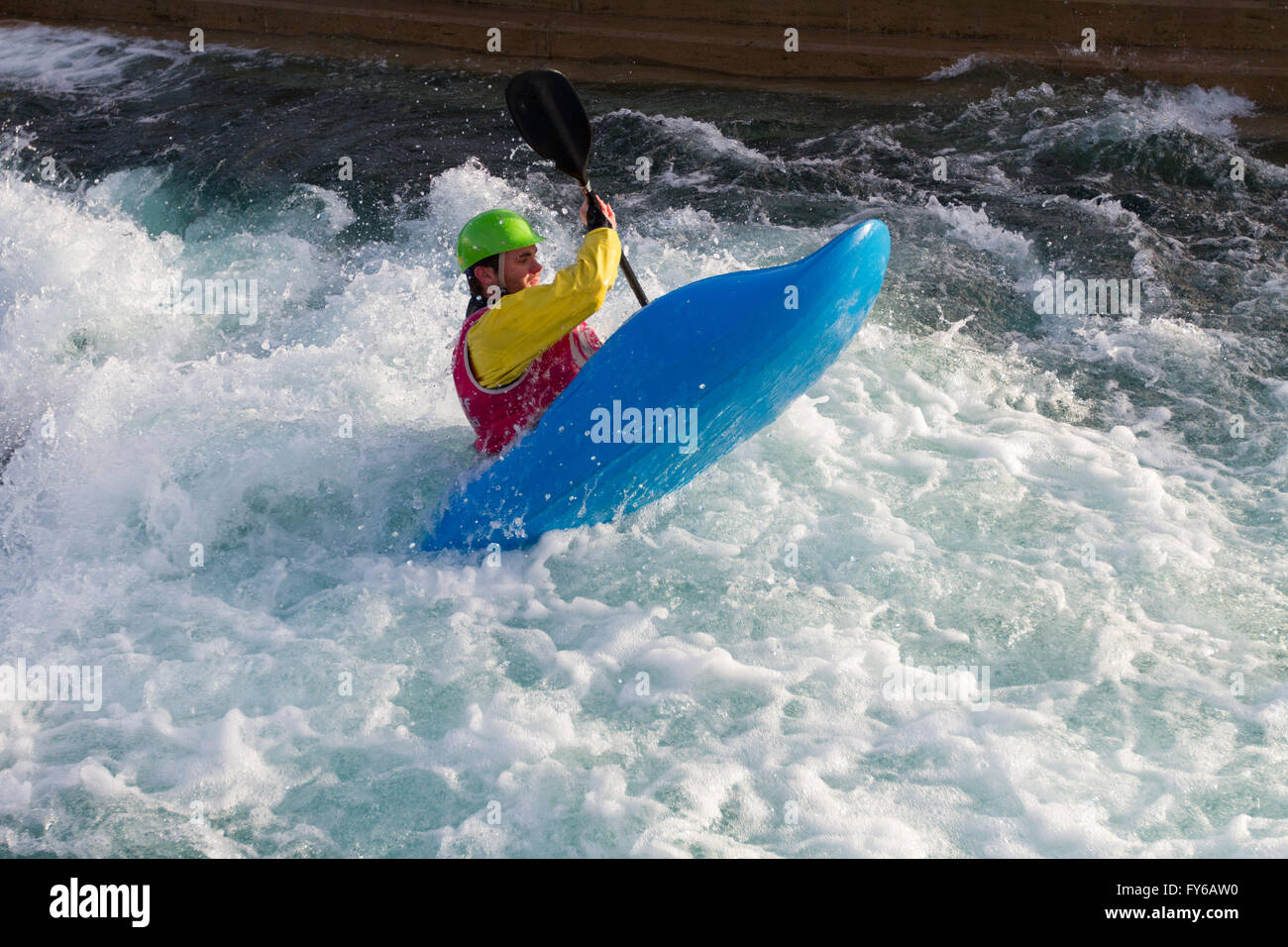 Young male man paddling a kayak in white water. The kayak has it's nose ...