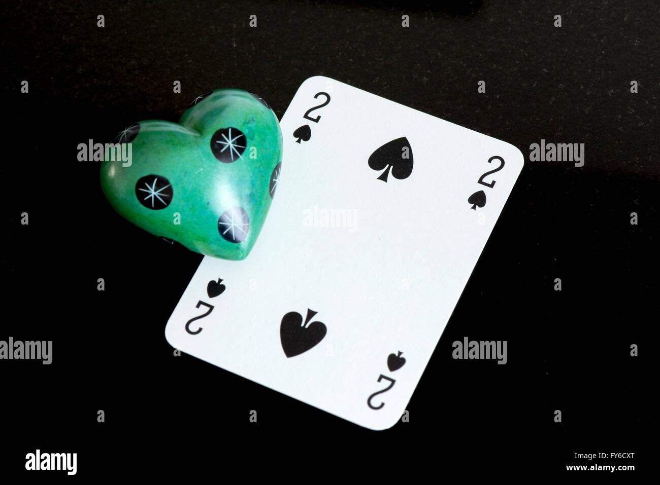 Playing card and stone love on black table Stock Photo - Alamy