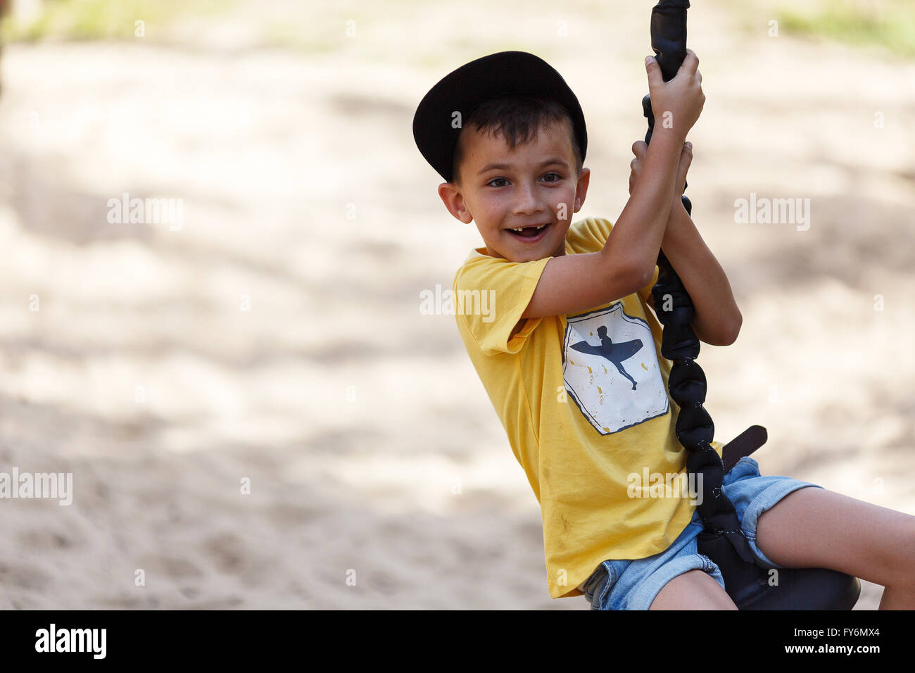 Little blonde Boy on Rope Swing and smile Stock Photo - Alamy