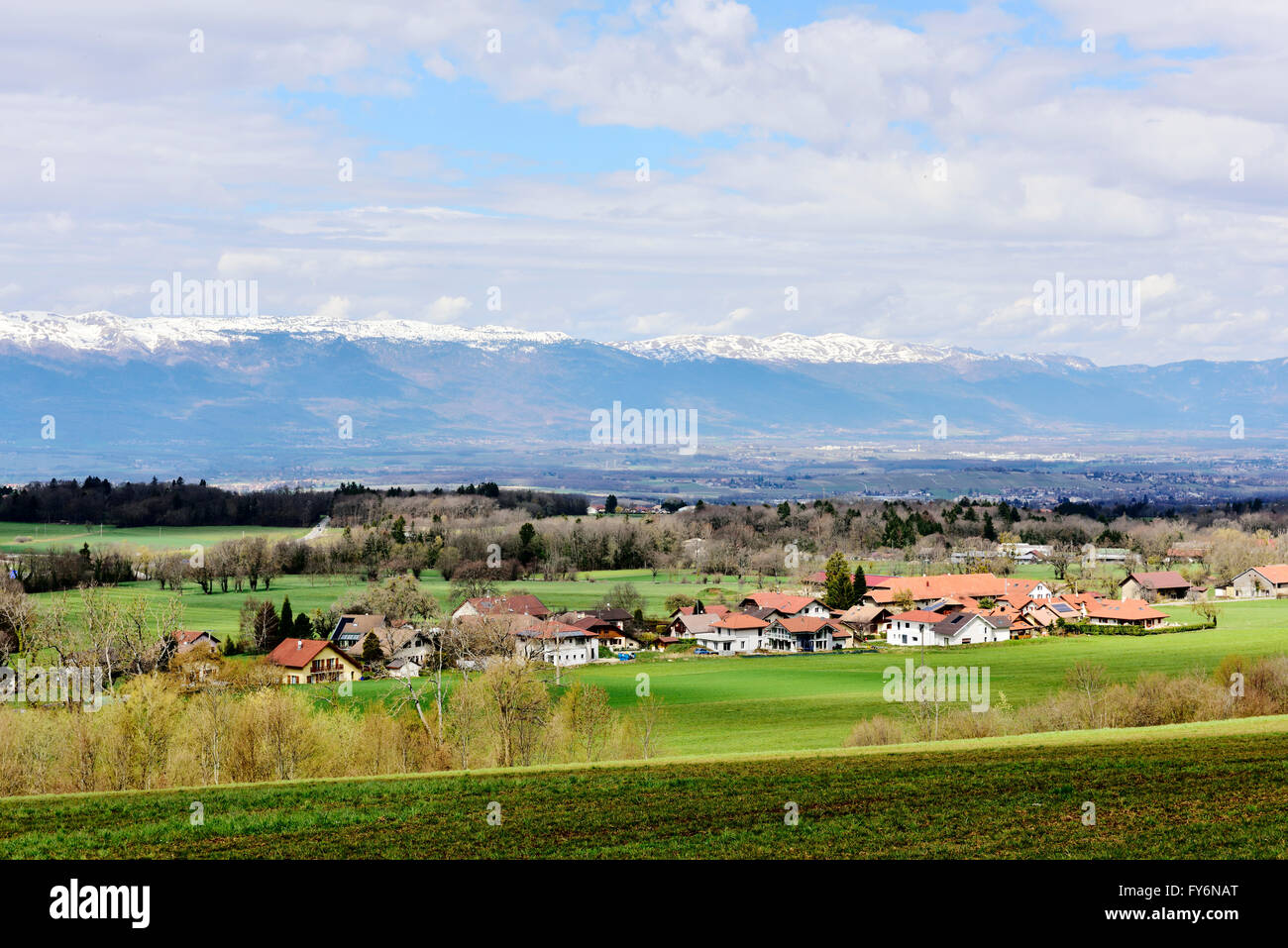 French countryside with village and in distance snow capped mountains ...