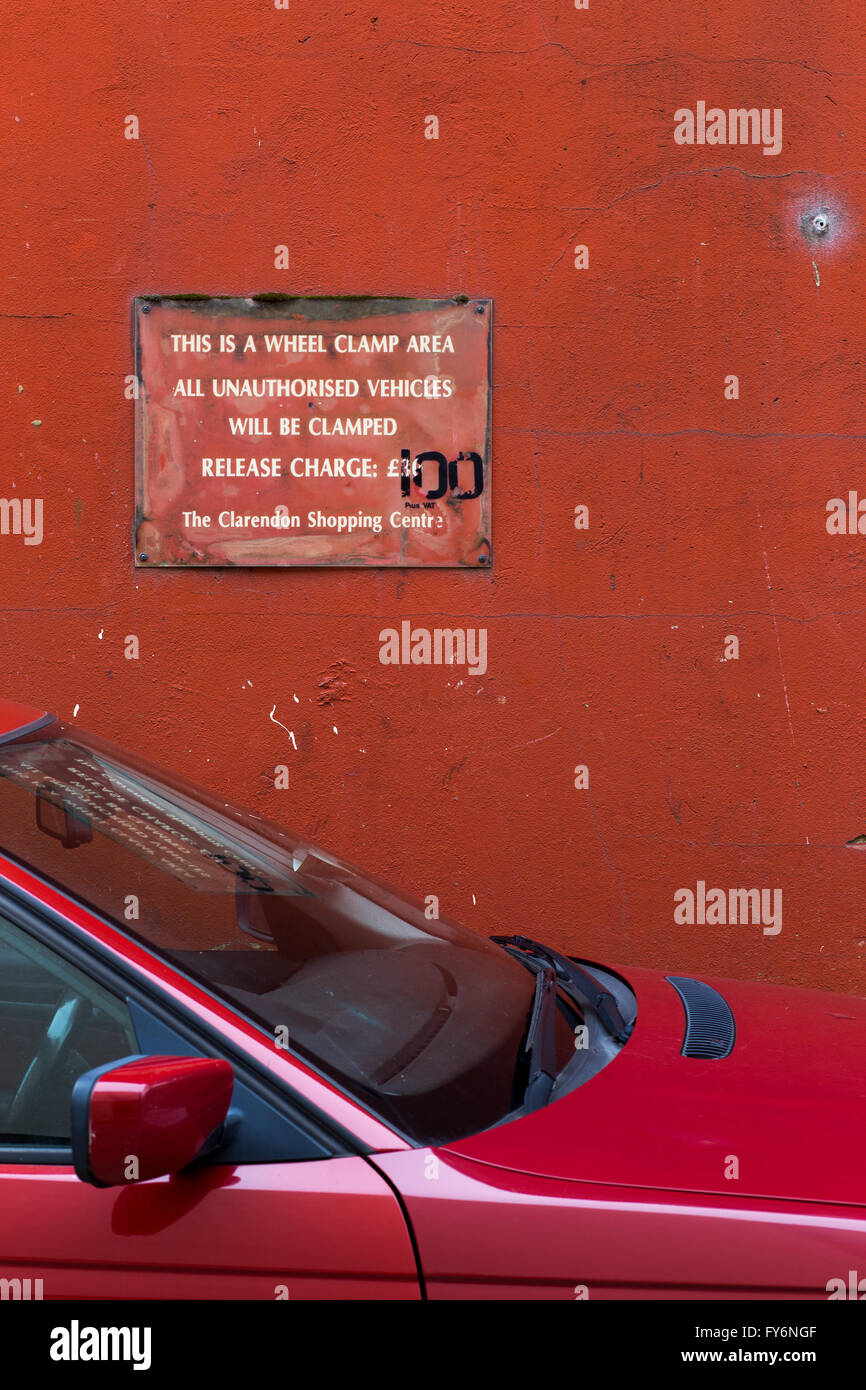 Sign on red wall - This is a Wheel Clamp Area All Unauthorised Vehicles ...