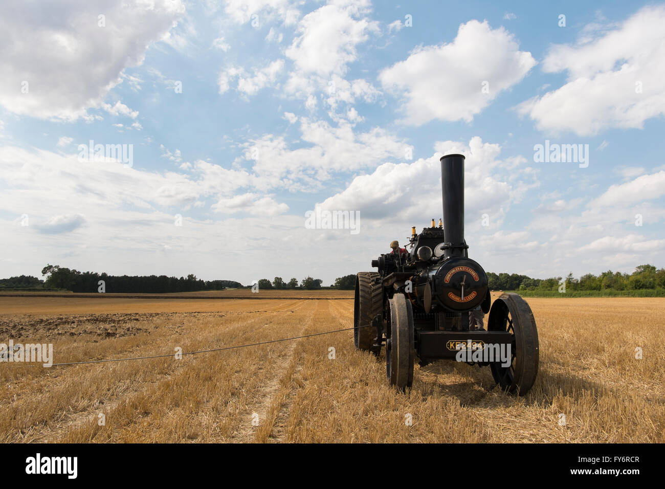 Traction steam engine pulling a vintage plough across a field at the ...