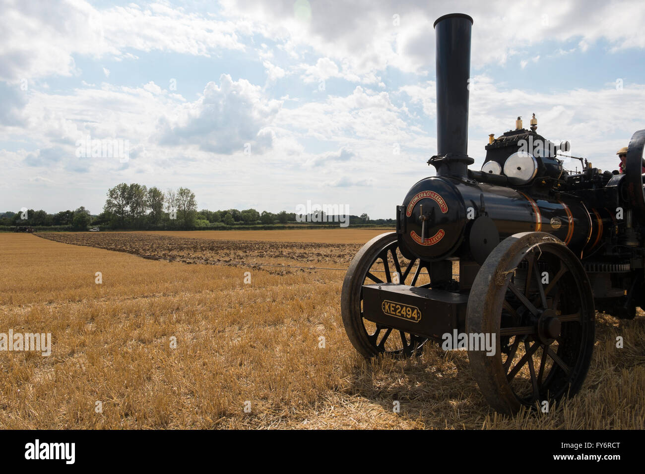 Traction steam engine pulling a vintage plough across a field at the ...