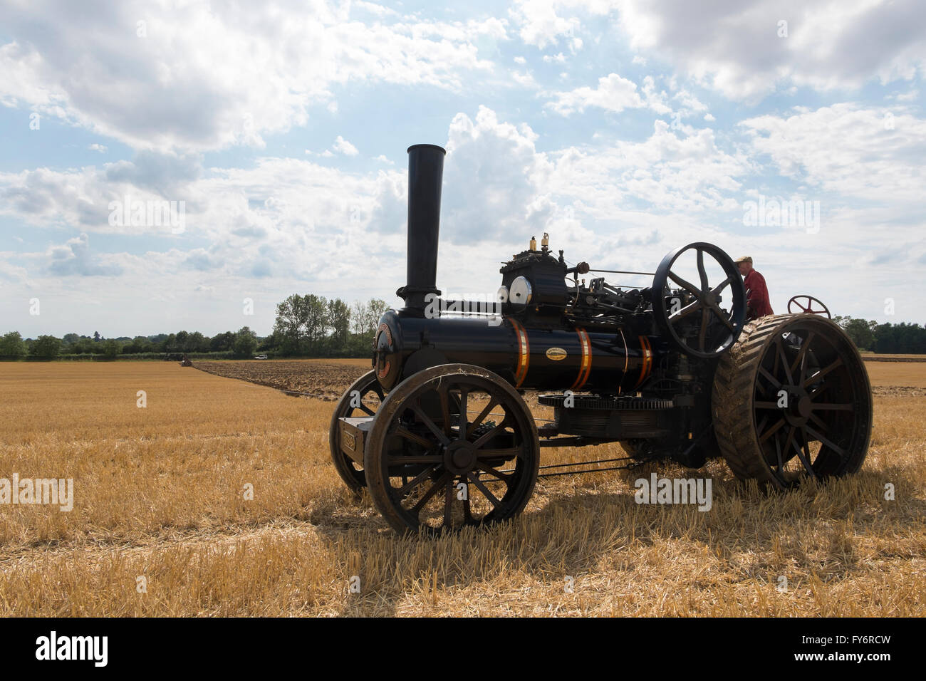 Traction steam engine pulling a vintage plough across a field at the ...