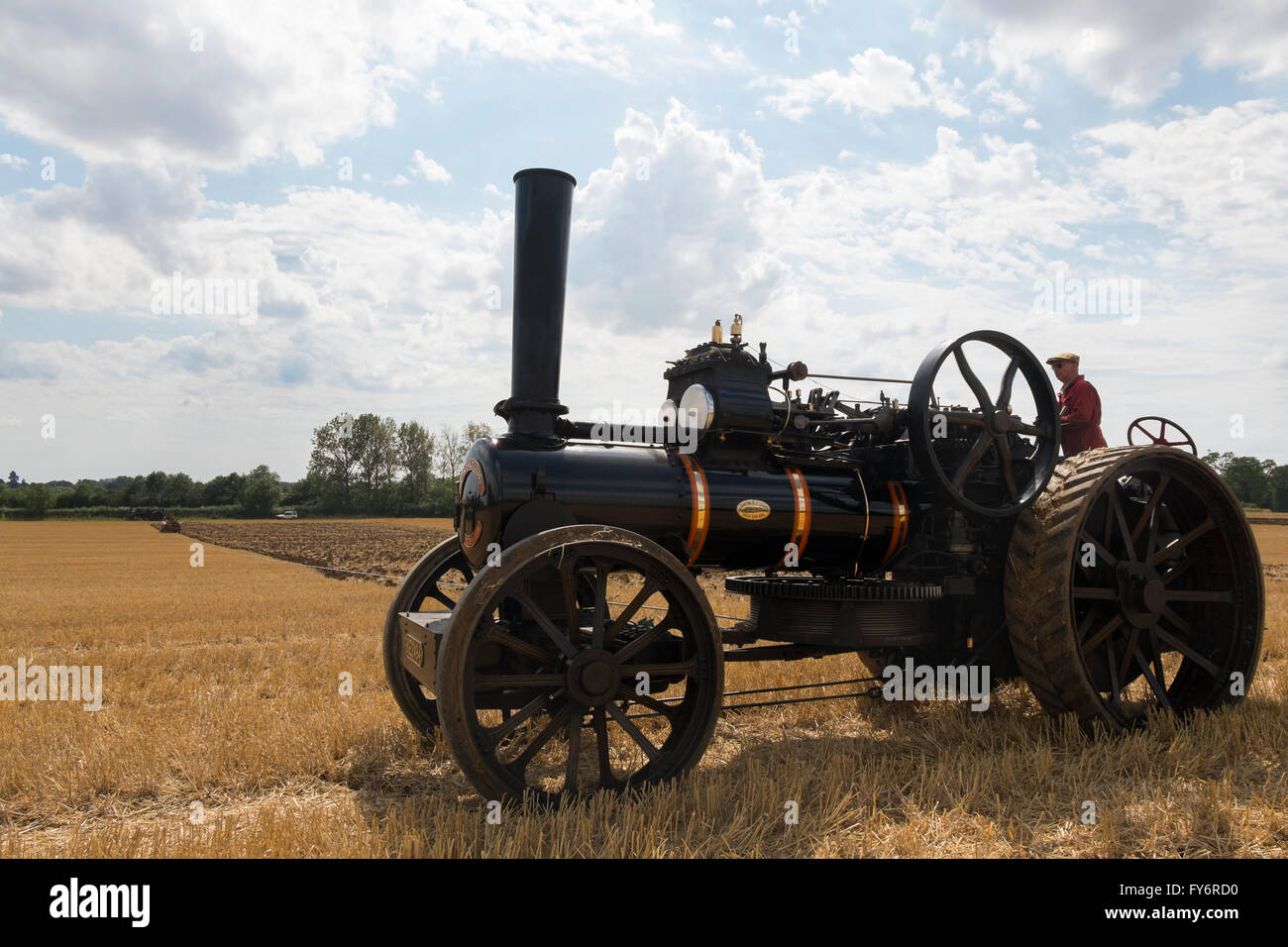 Traction steam engine pulling a vintage plough across a field at the ...