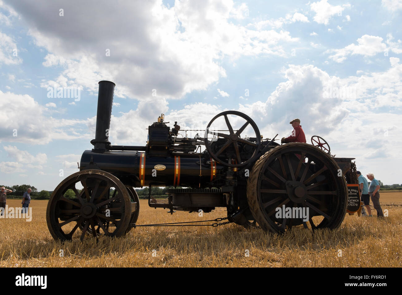 Traction steam engine pulling a vintage plough across a field at the ...