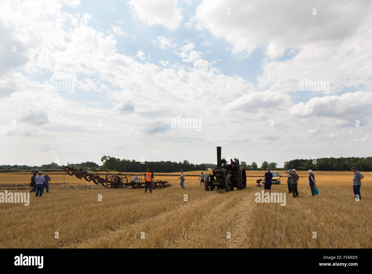 Traction steam engine pulling a vintage plough across a field at the ...