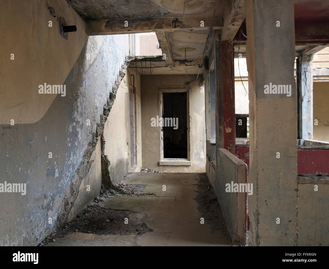 Inside of a falling apart building leading towards a doorway past a ...