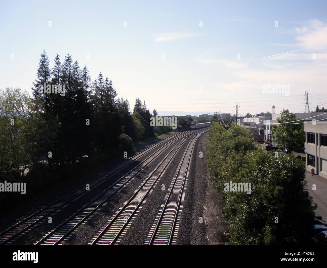 four lane train track with distant train rolling though on the San ...