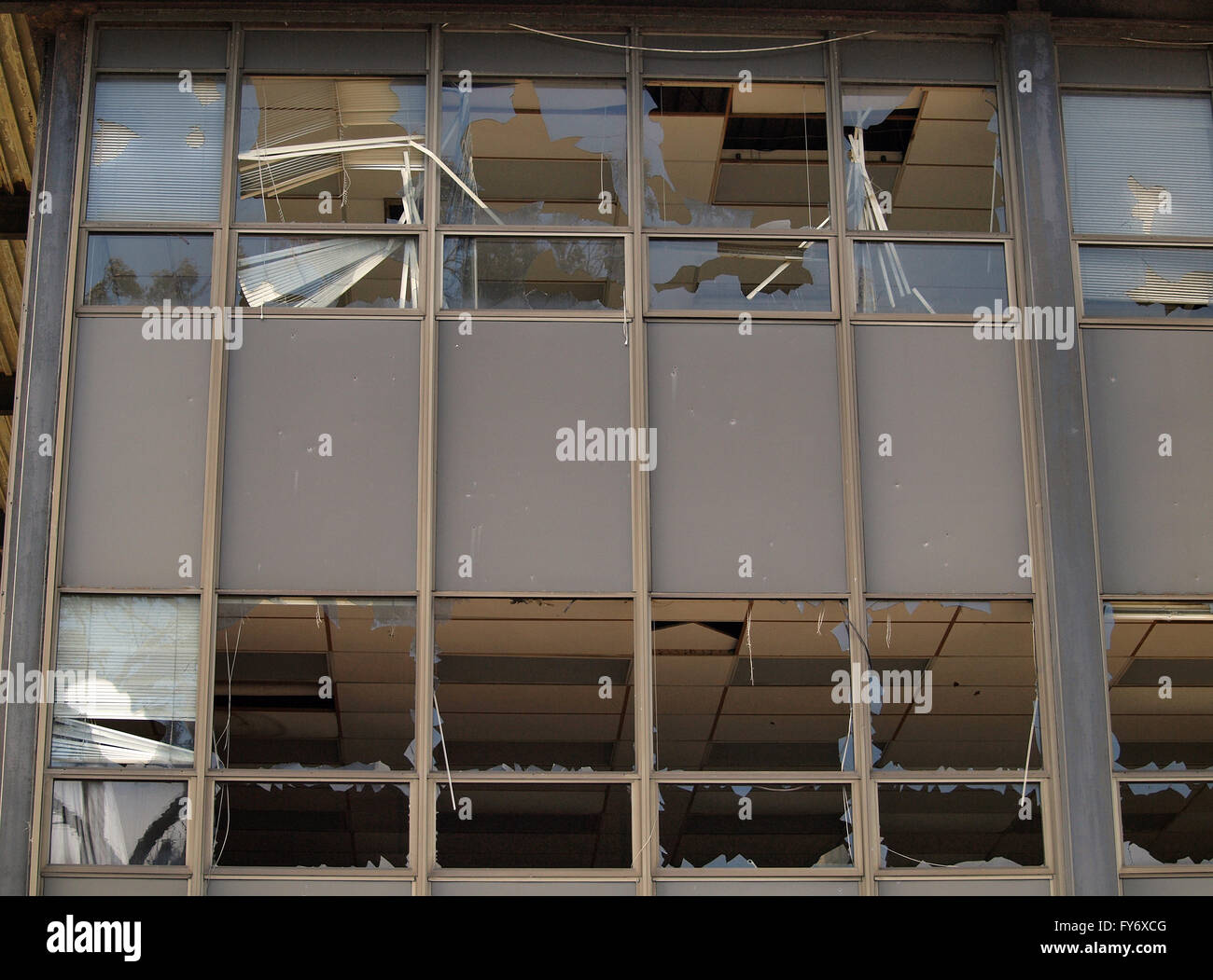 Broken windows of an office building with blinds hanging out the ...