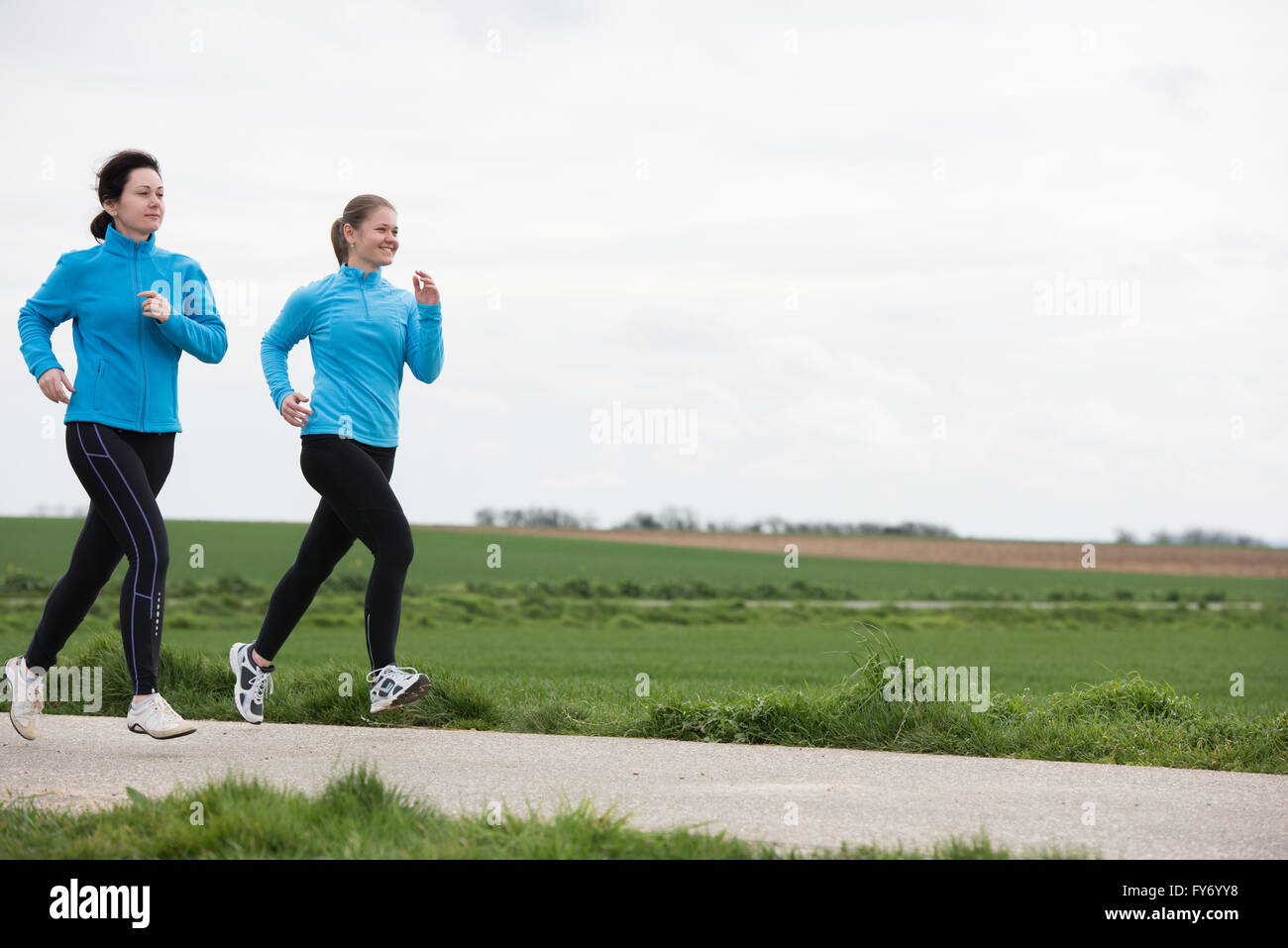 two women, 40 and 20 years old, jogging (running) outdoors Stock Photo ...