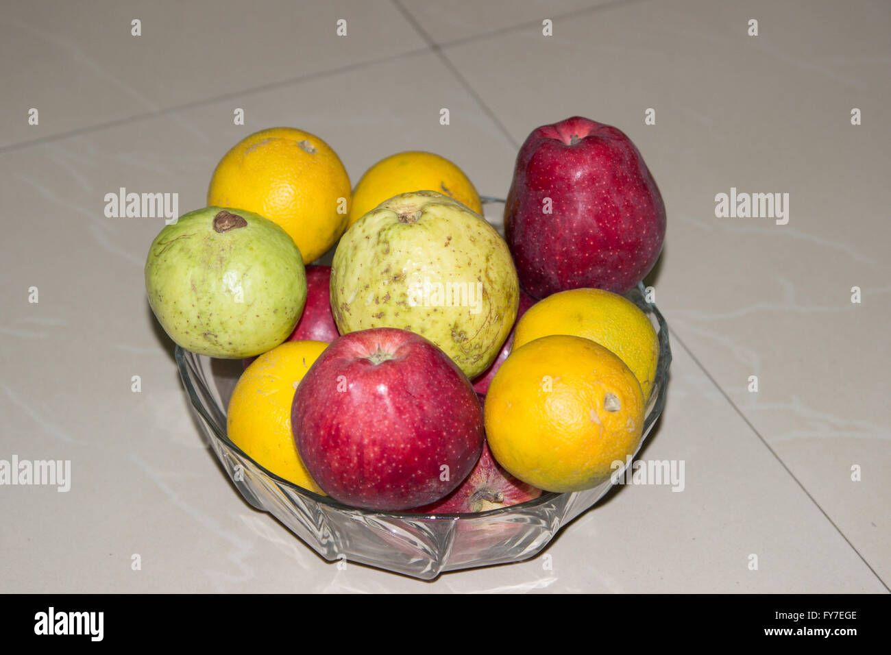 Bowl of fruits with apples, sweet lime and gauva in a glass bowl ...