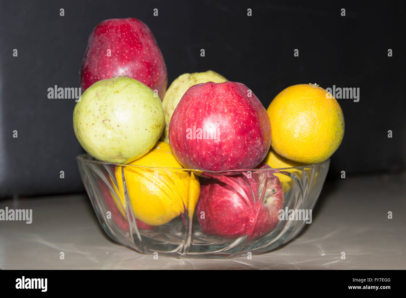 Bowl of fruits with apples, sweet lime and gauva in a glass bowl ...