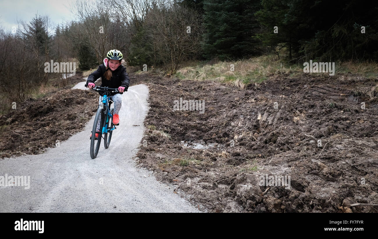 A girl rides a bike along an off-road trail / track smiling Stock Photo ...