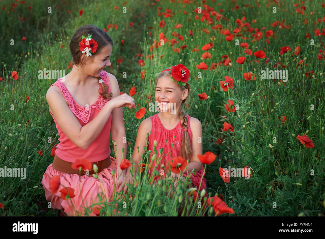 two beautiful young sisters walking in poppy field Stock Photo - Alamy