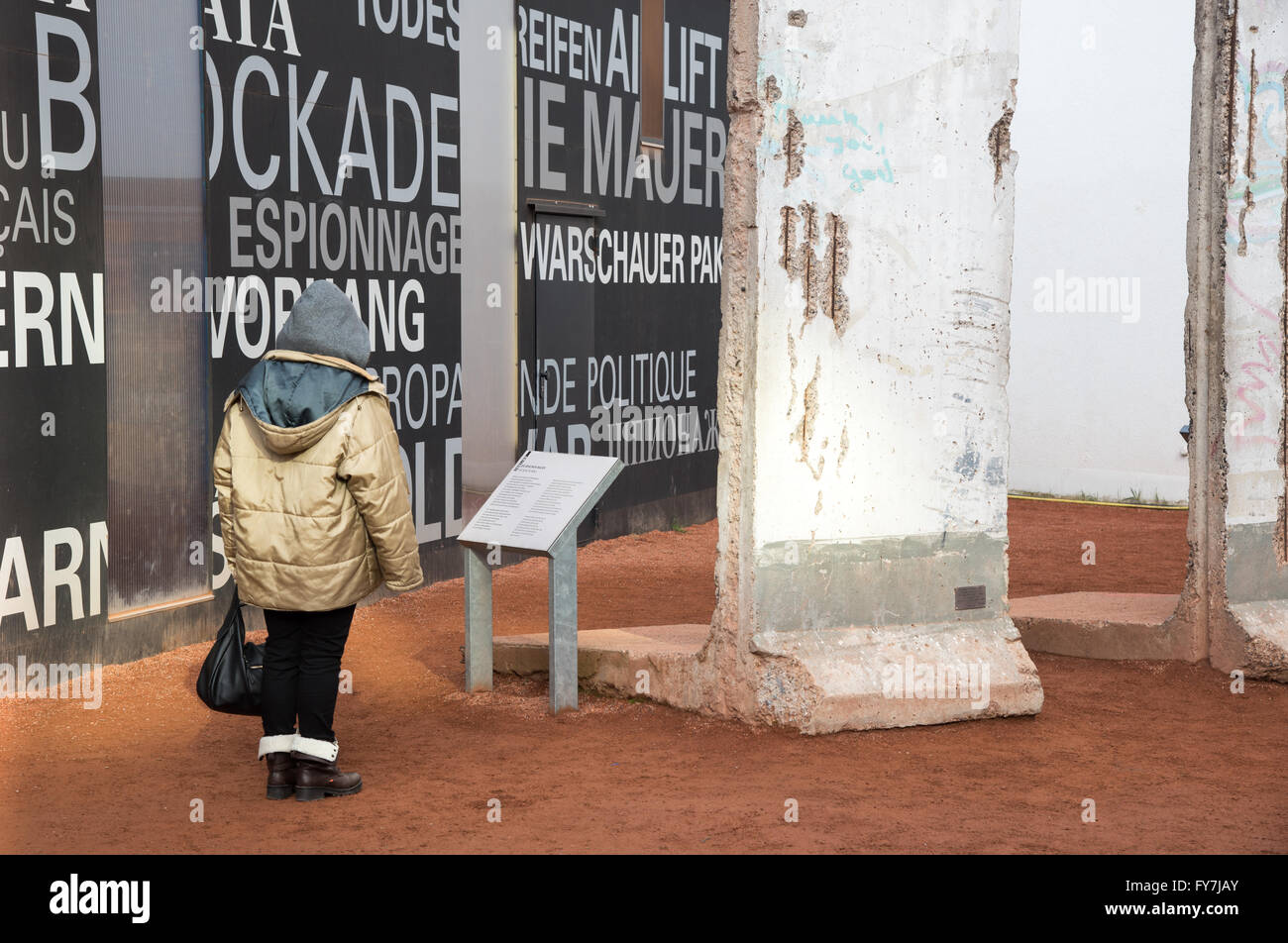 Woman standing in front of a part of Berlin wall near famous Checkpoint ...