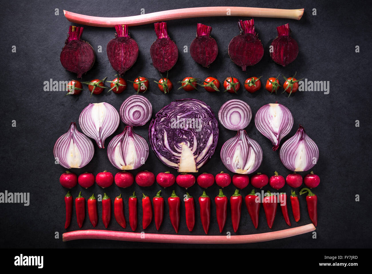 Red vegetables cut in halves, flat lay design on dark background ...