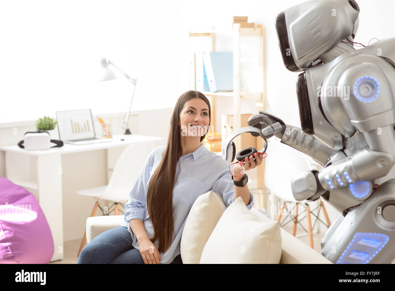 Nice girl giving headphones to modern robot Stock Photo - Alamy