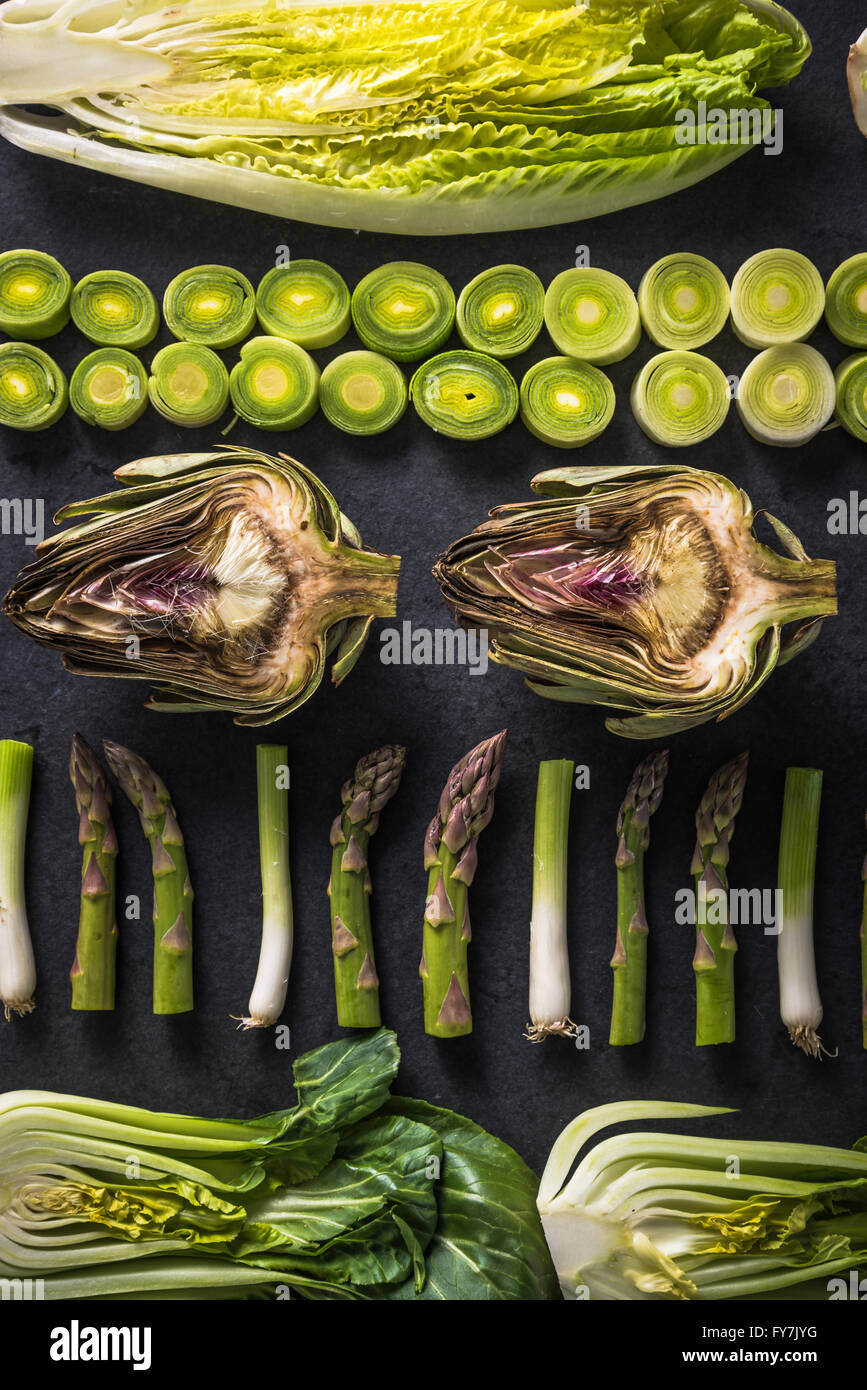 Green vegetables cut in halves, flat lay design on dark background ...