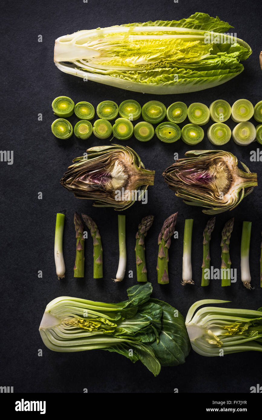 Green vegetables cut in halves, flat lay design on dark background ...