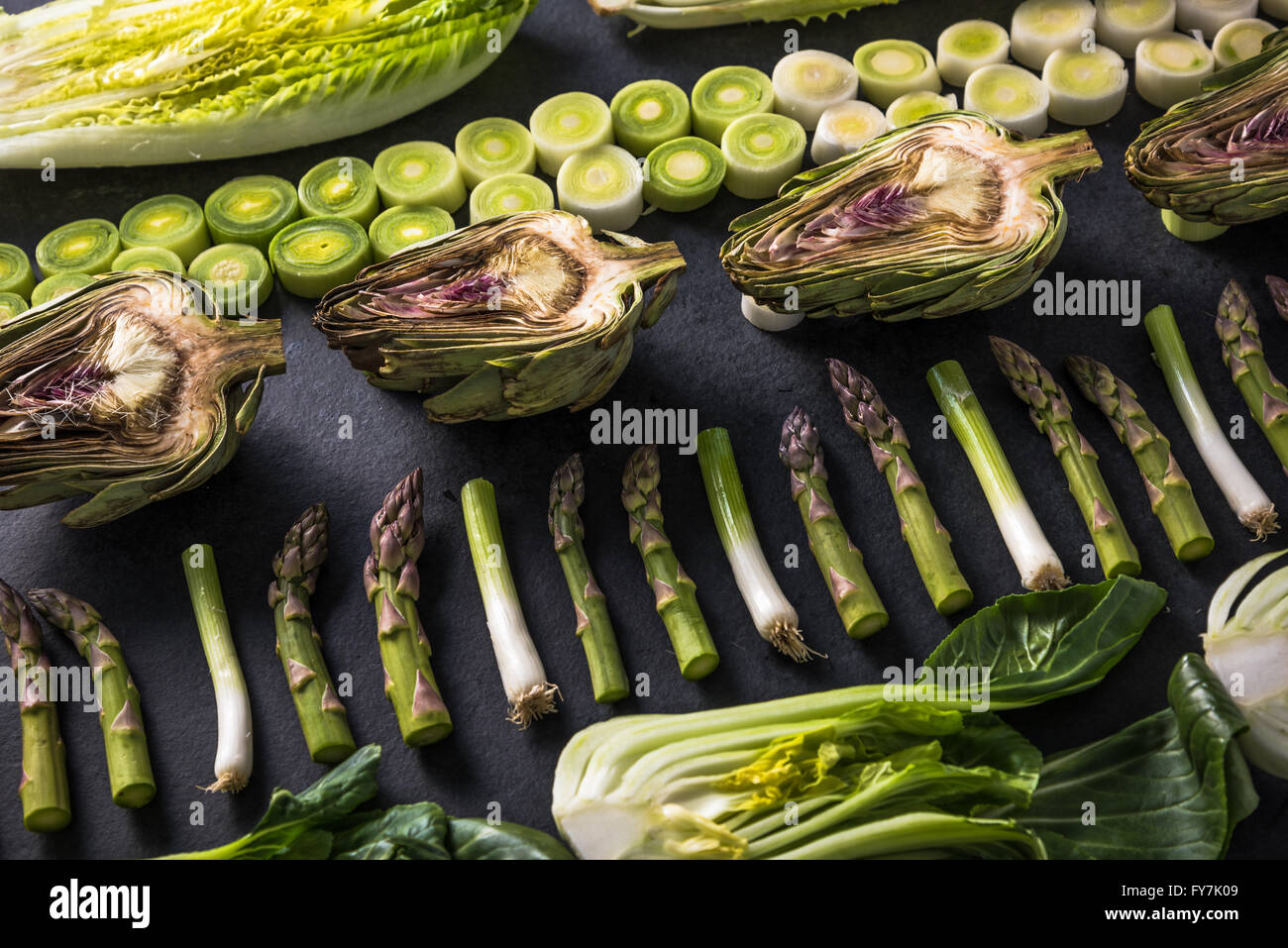 Green vegetables cut in halves, flat lay design on dark background ...