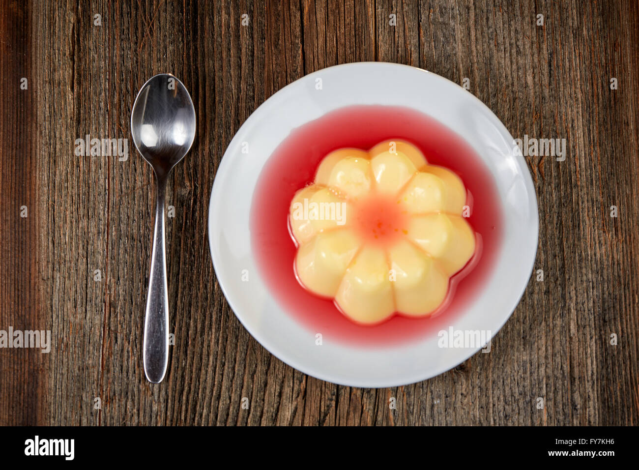 Yellow vanilla pudding with strawberry sauce on rown wooden table Stock ...