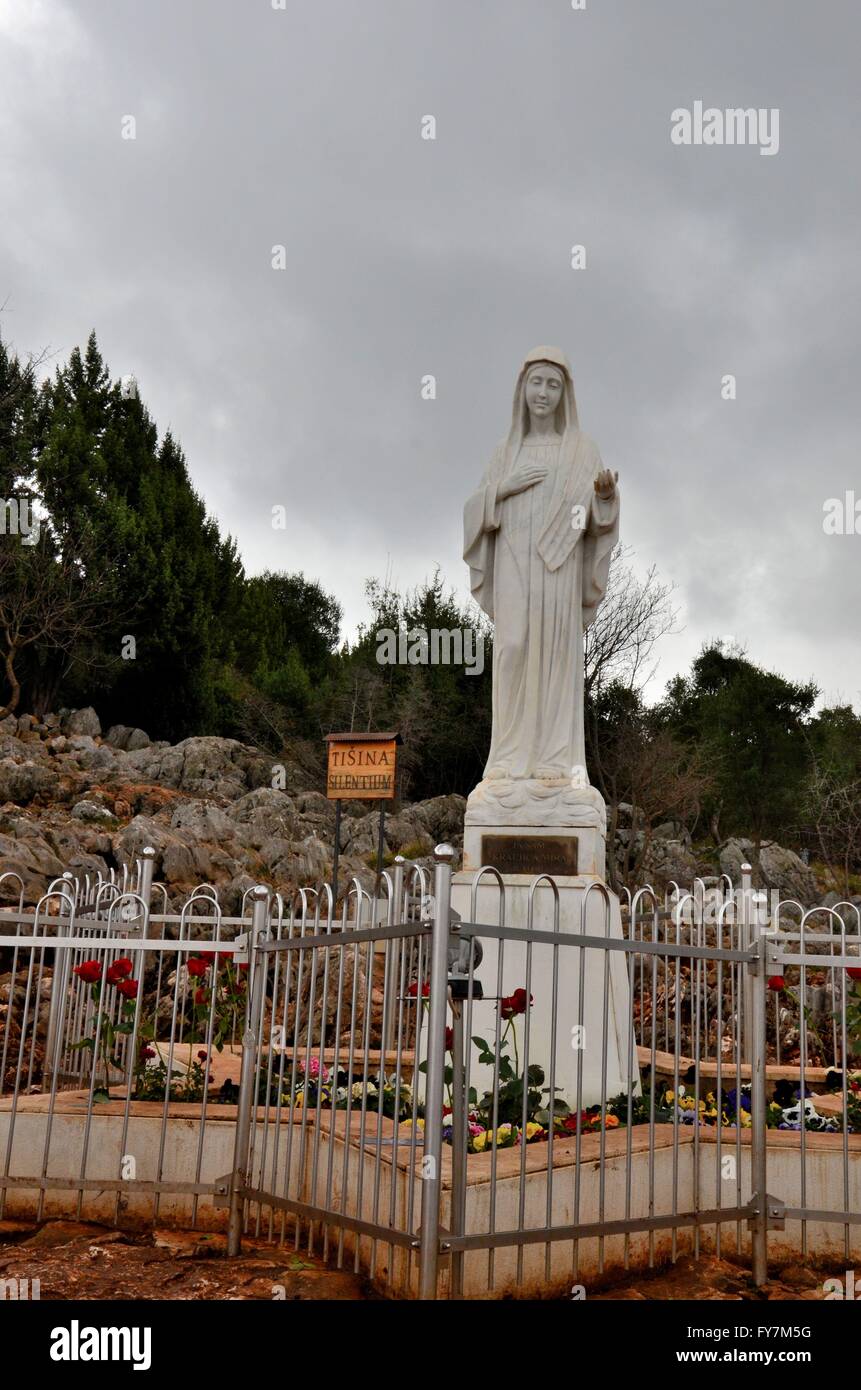 Statue of Virgin Mary with flower bed and surrounded by fence at ...