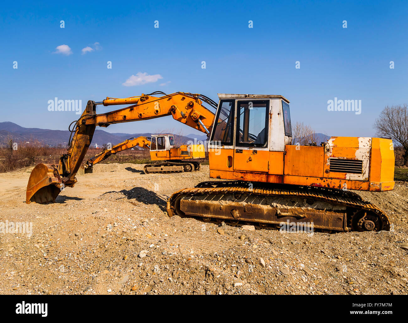 Old and rusty excavators digging out pebbles from the bank of the river ...